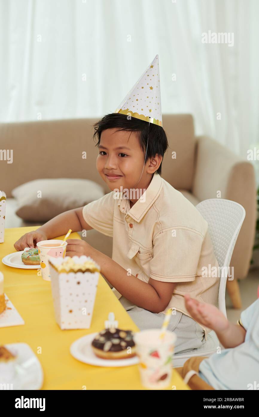Smiling preteen Asian boy eating sweets at birthday party Stock Photo ...