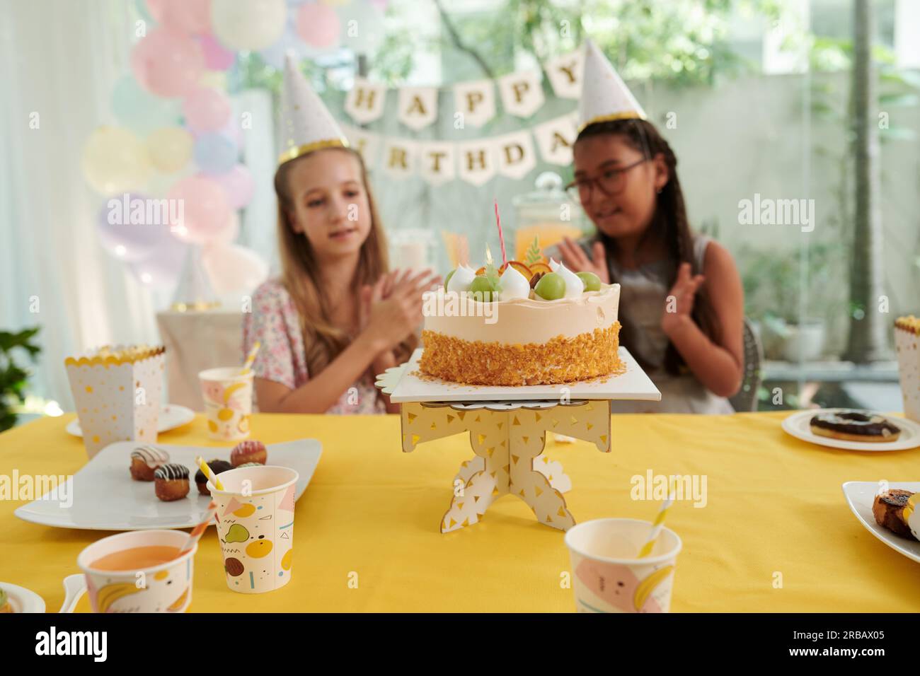 Birthday party guests clapping to decorated cake brought to table Stock ...