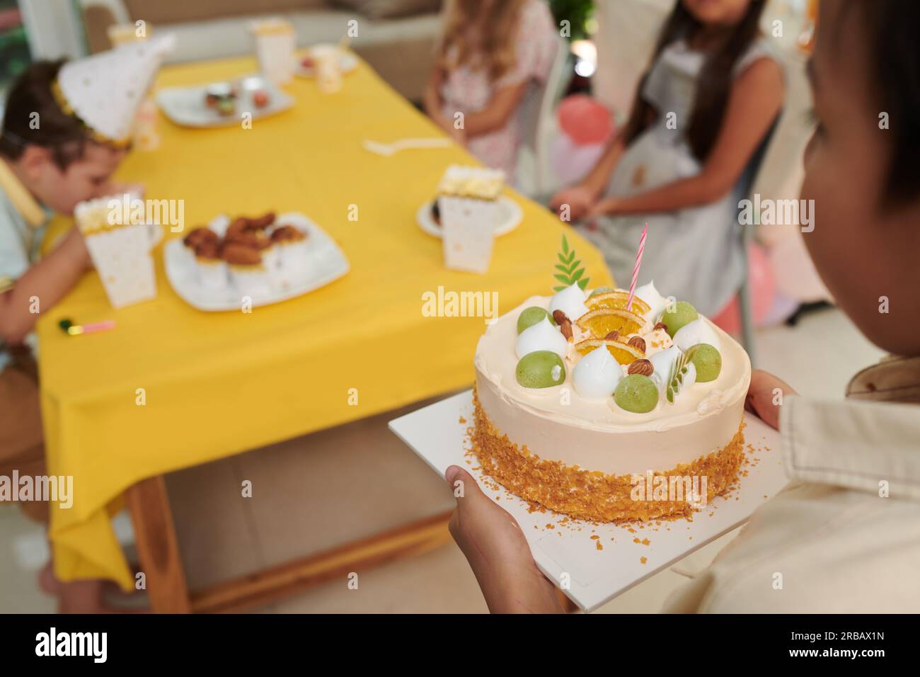 Boy bringing birthday cake to table to share with friends Stock Photo ...
