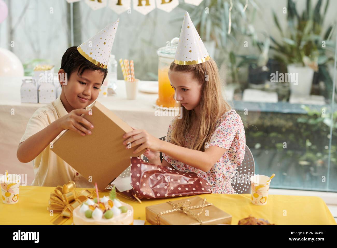 Excited kid and his friend opening birthday presents after party Stock ...
