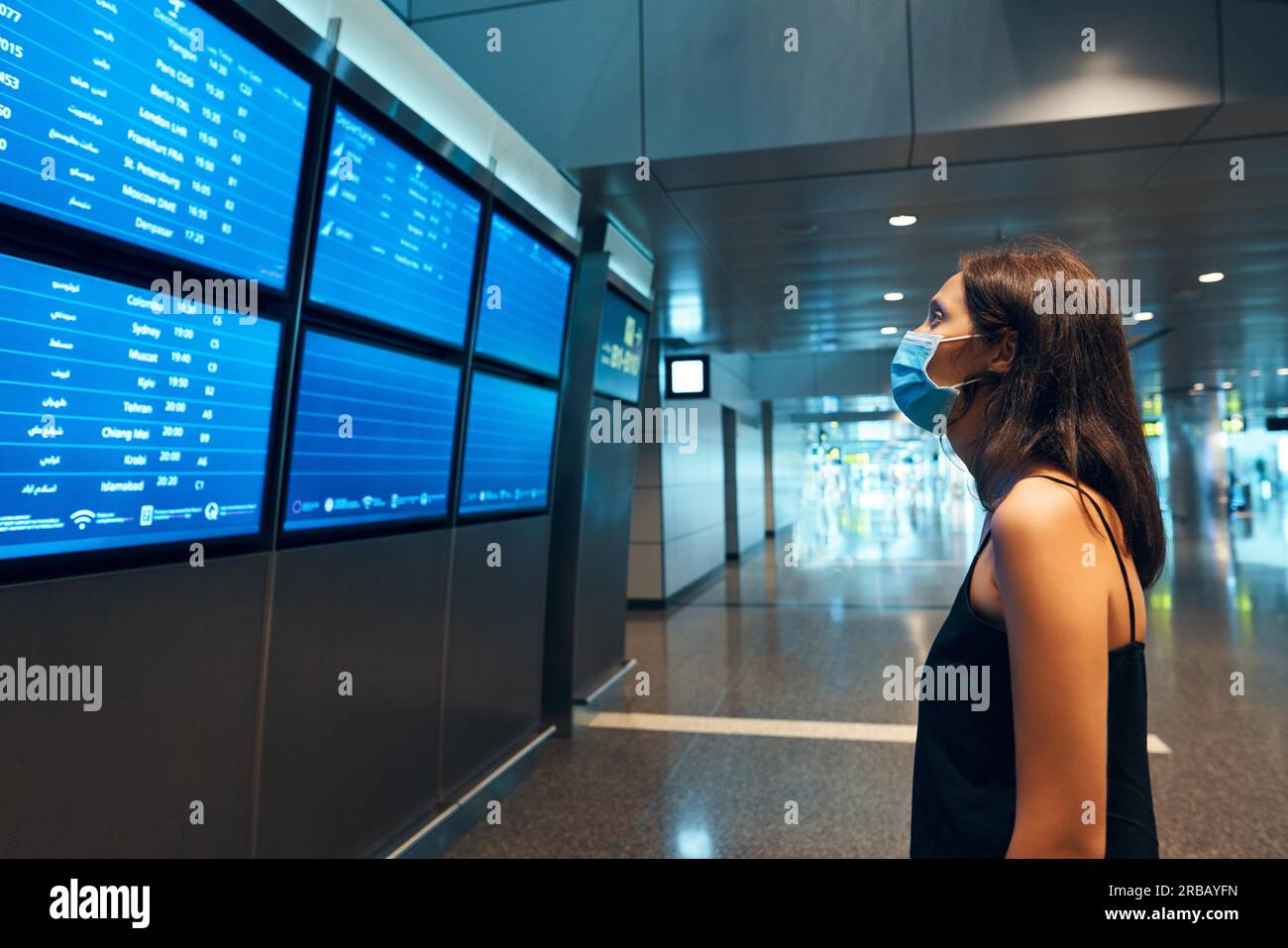 Woman in virus protection face mask looking at information board ...