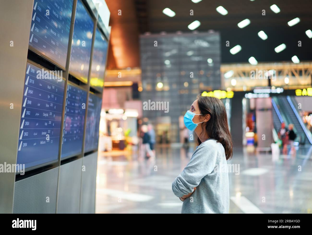 Woman in virus protection face mask looking at information board ...