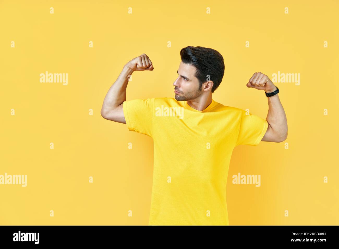 Handsome muscular man shows muscles on his arms on yellow background ...