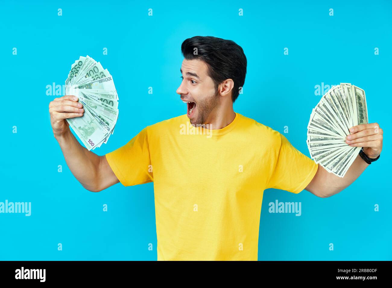 Happy excited man holding money banknotes on blue background. Business ...