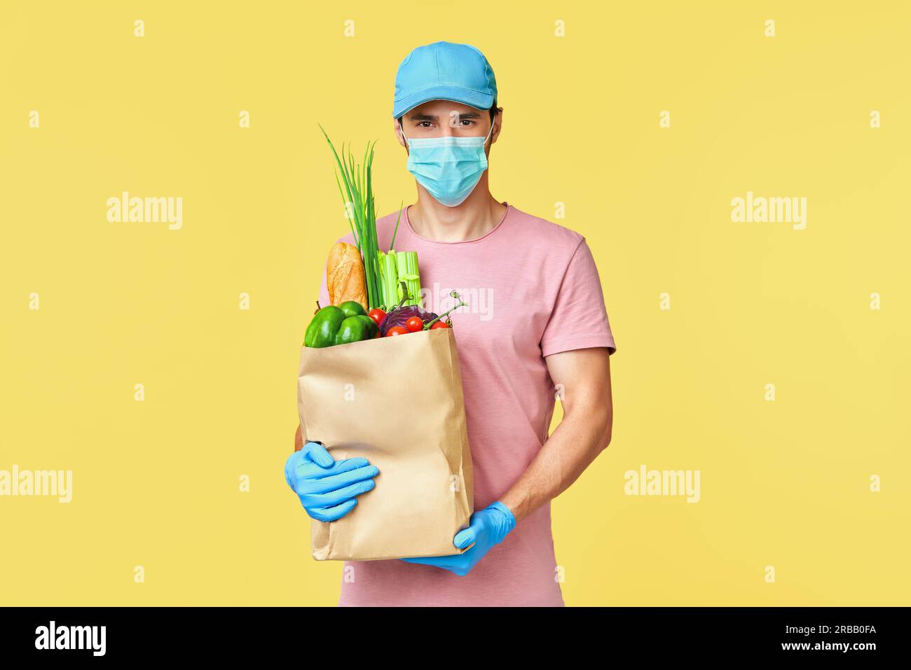 Delivery man giving food in paper bag wearing face mask and gloves as ...