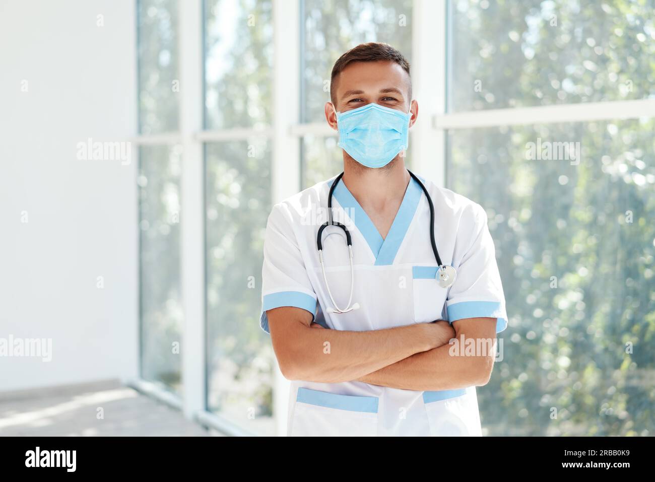 Confident male doctor wearing medical mask with arms crossed in ...