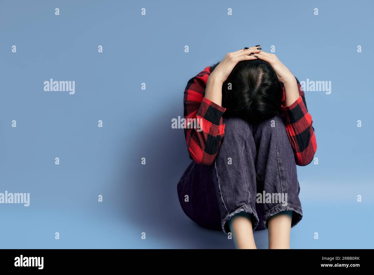 Depressed young woman sitting alone on the floor with copy space ...