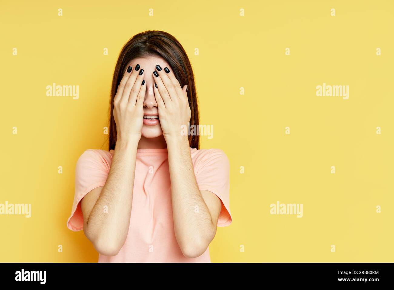 Happy excited woman close face by hands waiting for surprise on yellow ...