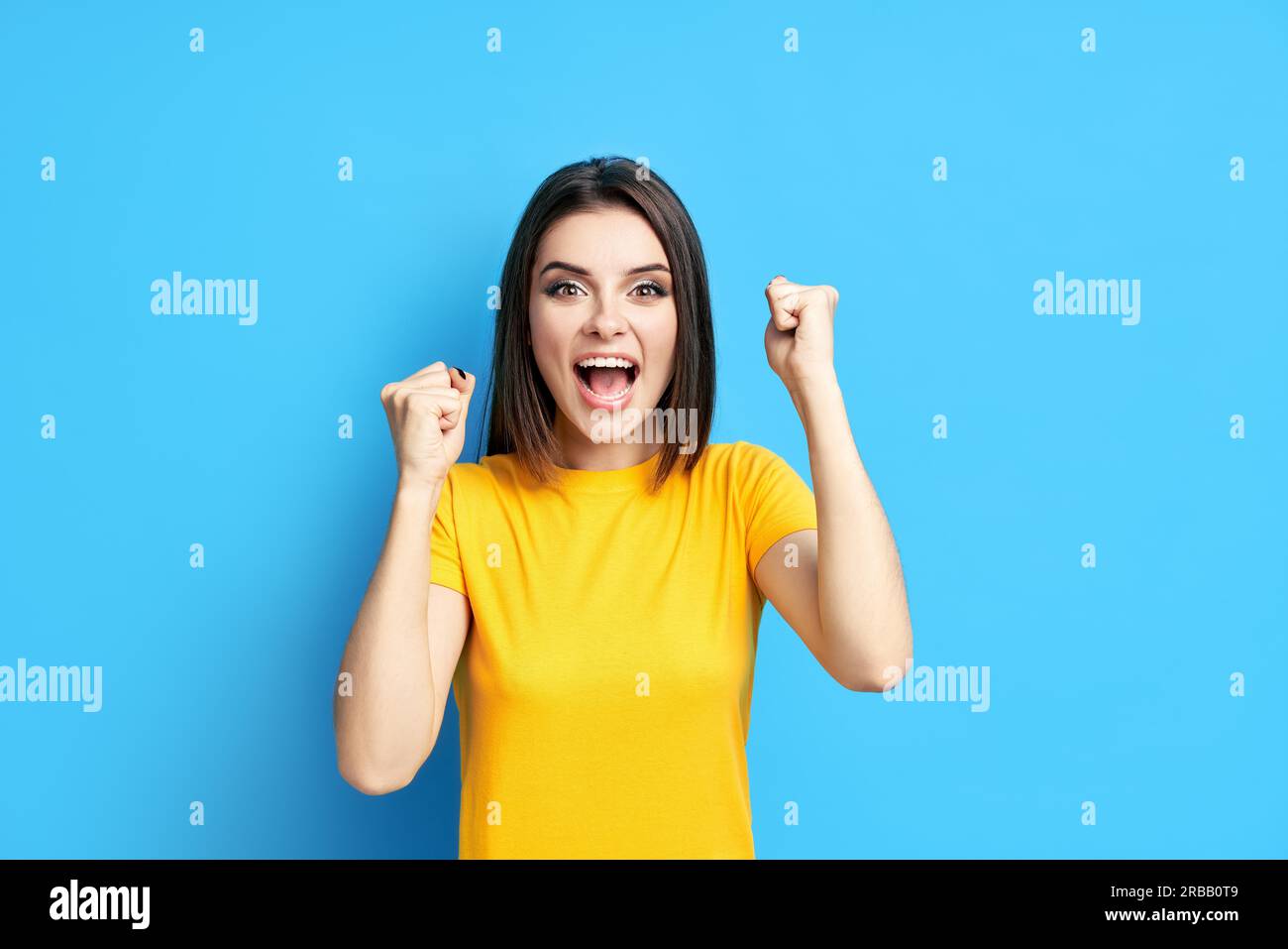 Happy excited young woman celebrate success with hands up isolated on ...