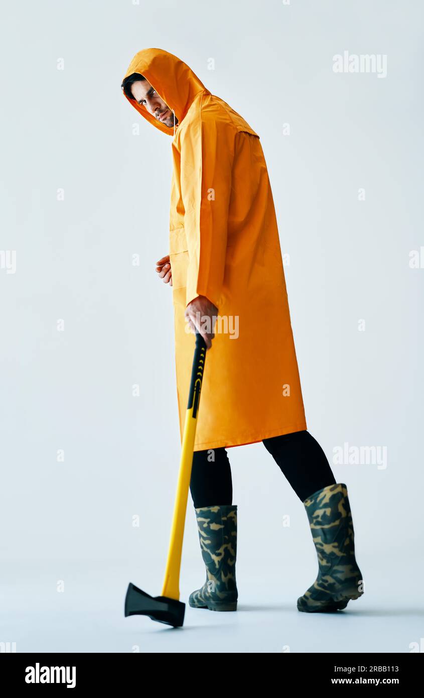 Full length portrait of young spooky man in bright raincoat holding big ...