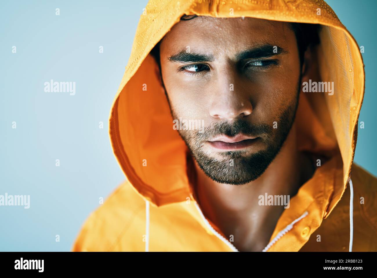 Close up portrait of young handsome man in bright orange raincoat ...