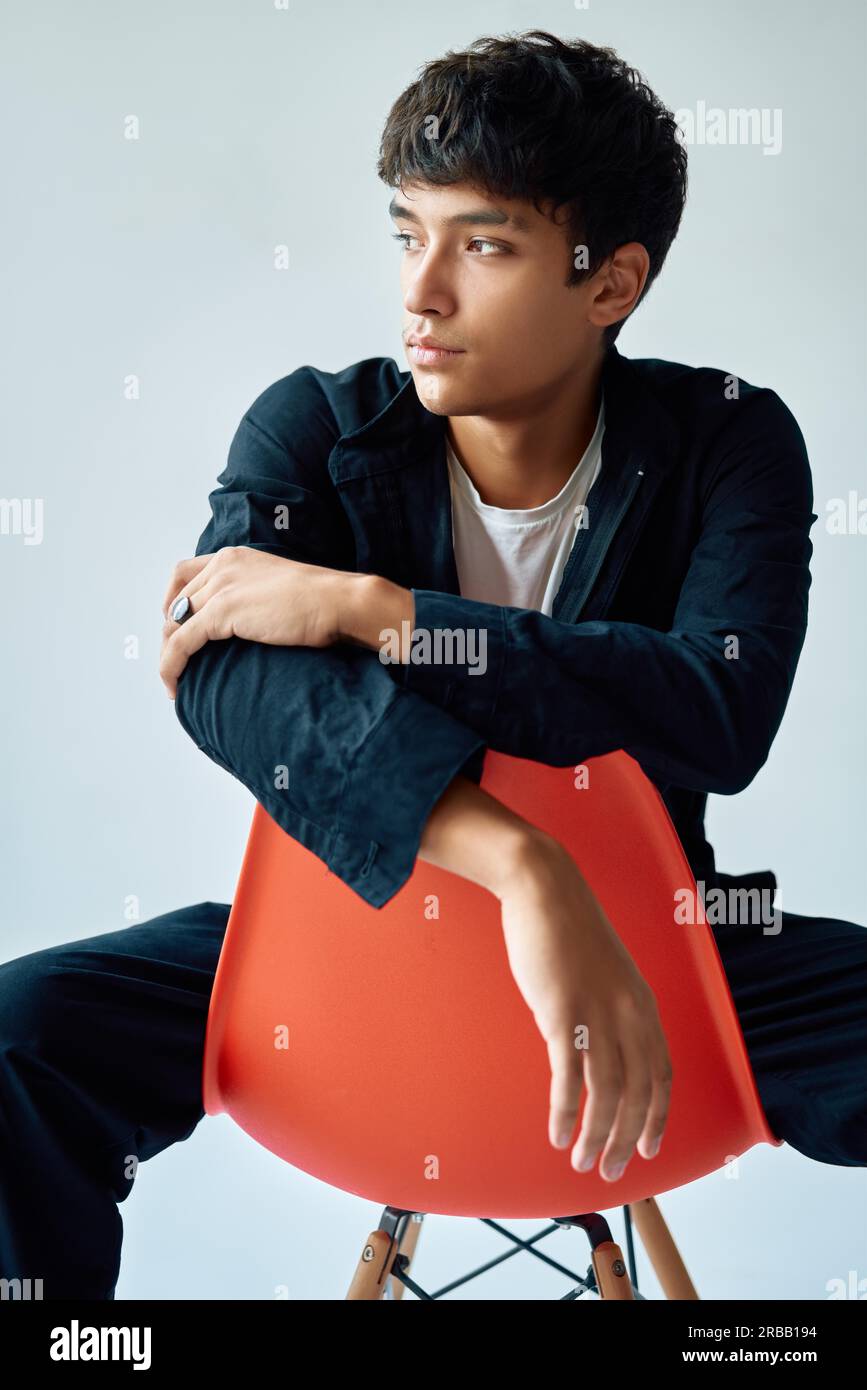 Stylish handsome young man posing on studio sitting on a chair on white ...