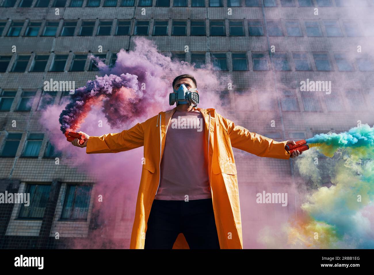 Young man in respirator mask hold smoke bombs in raised hands. protest ...