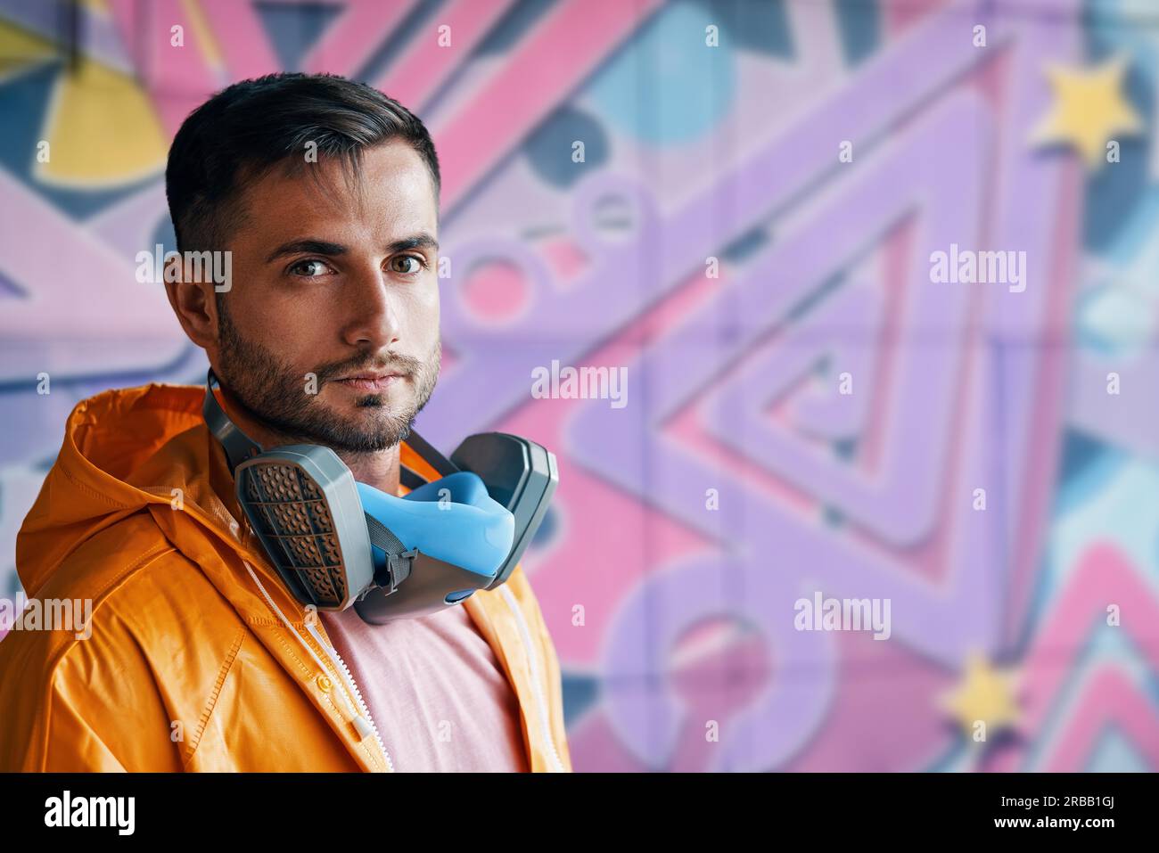 Portrait of handsome street artist staying on his graffiti painting ...