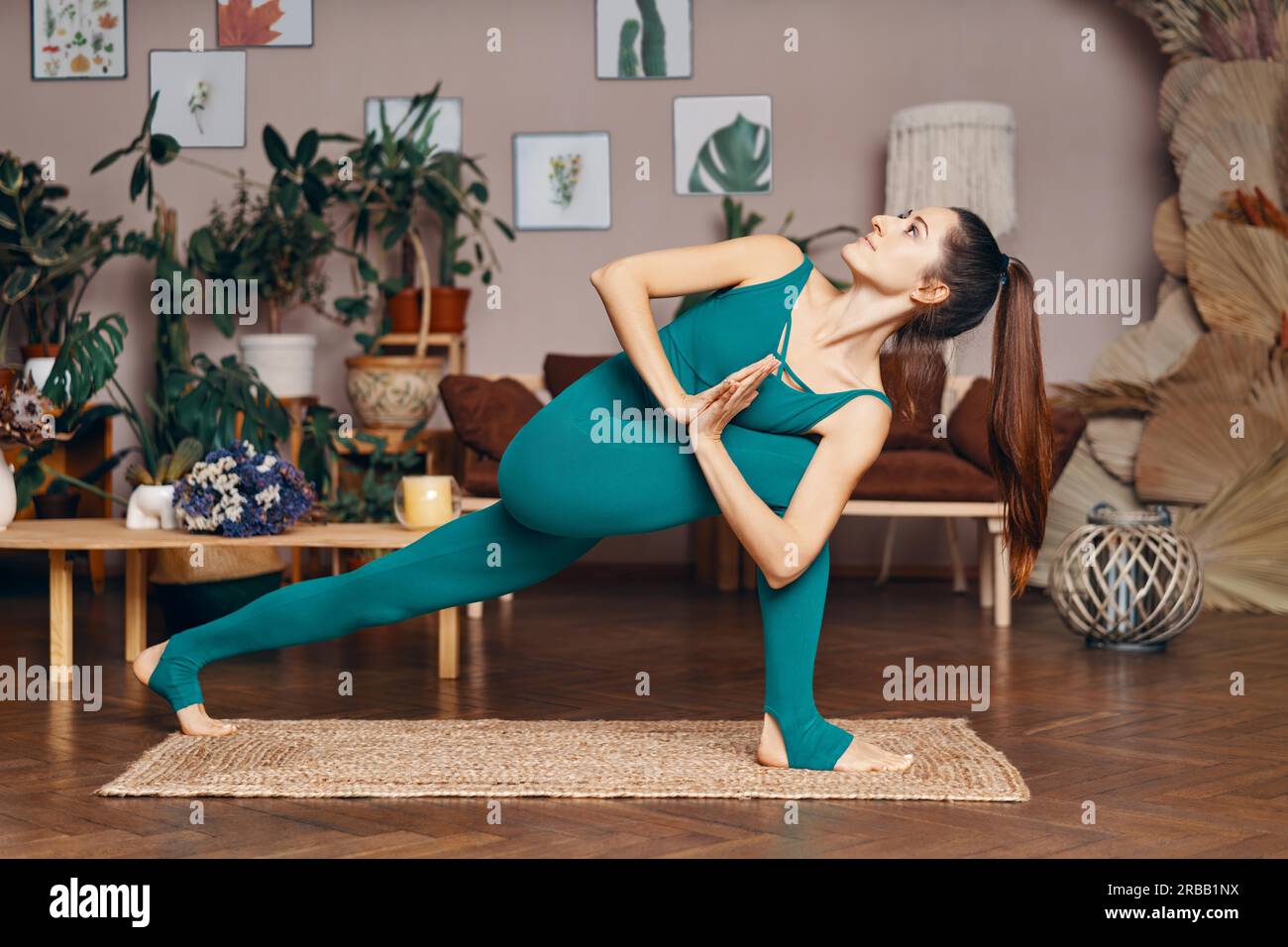 Young sporty woman practicing yoga at home doing half prayer twist pose ...