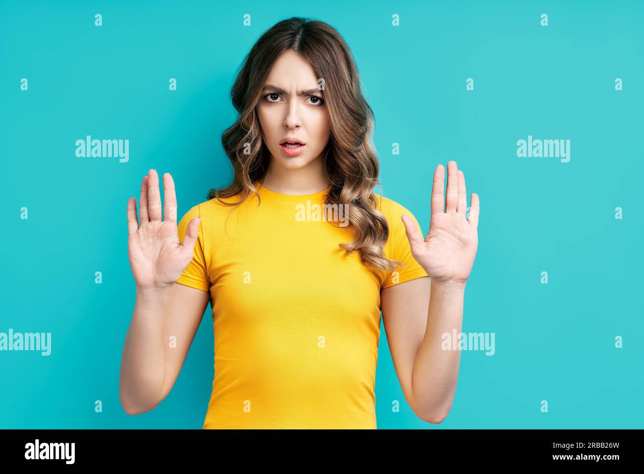 Young woman showing stop gesture with her hands isolated over blue ...