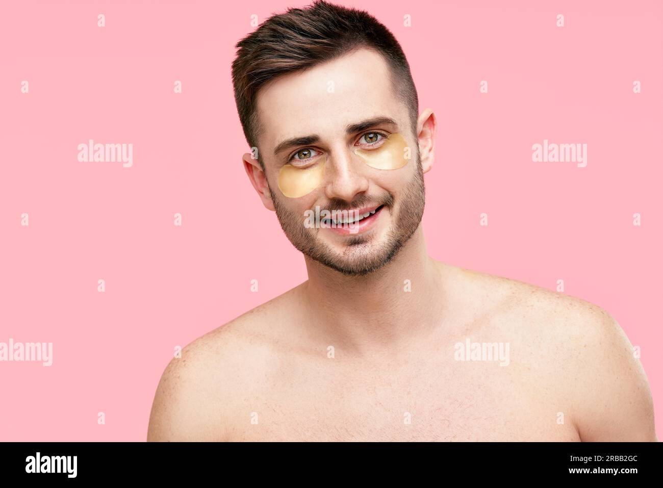 Portrait of smiling handsome man with golden eye patches on pink ...