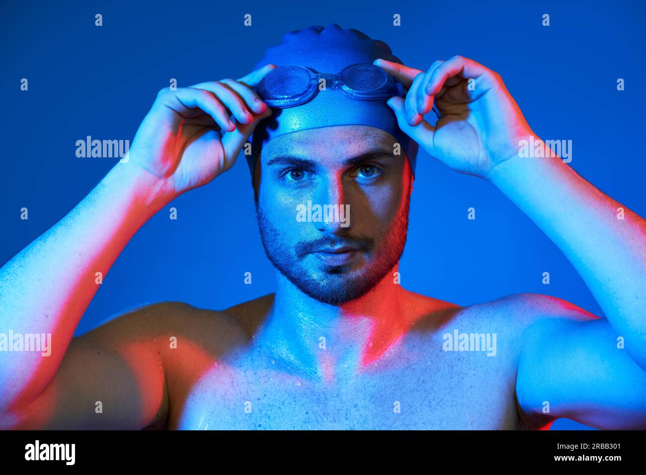 Close up portrait of handsome swimmer with goggles in red-pink neon ...