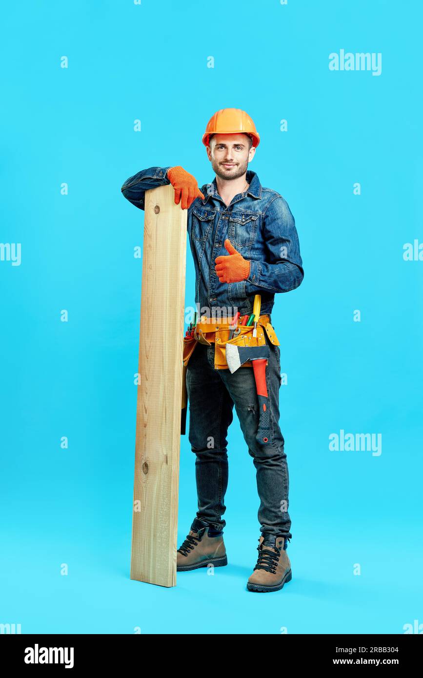 Full length portrait of young handsome carpenter hold pile of lumber ...