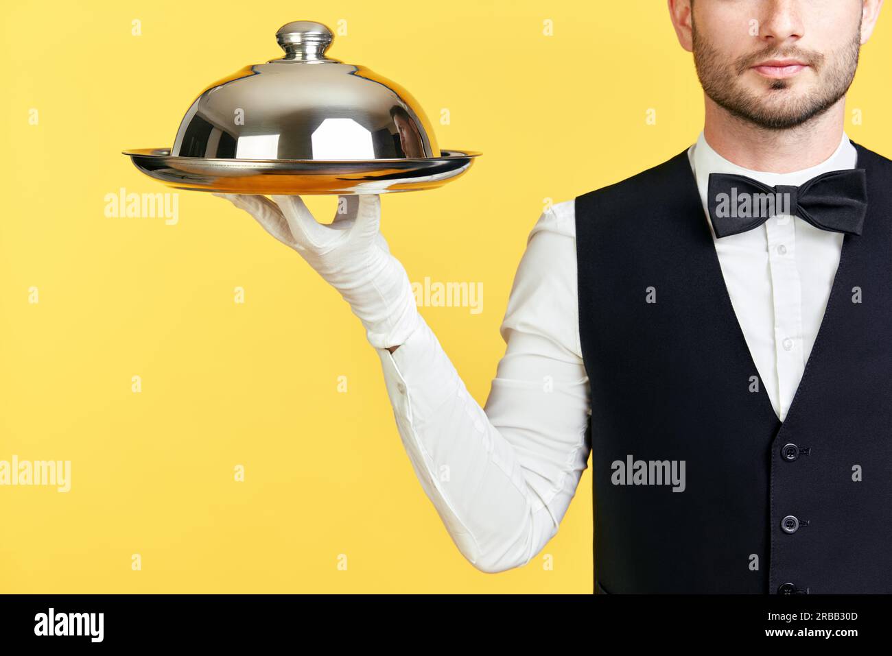 Handsome elegant waiter holding tray and cloche ready to serve on ...