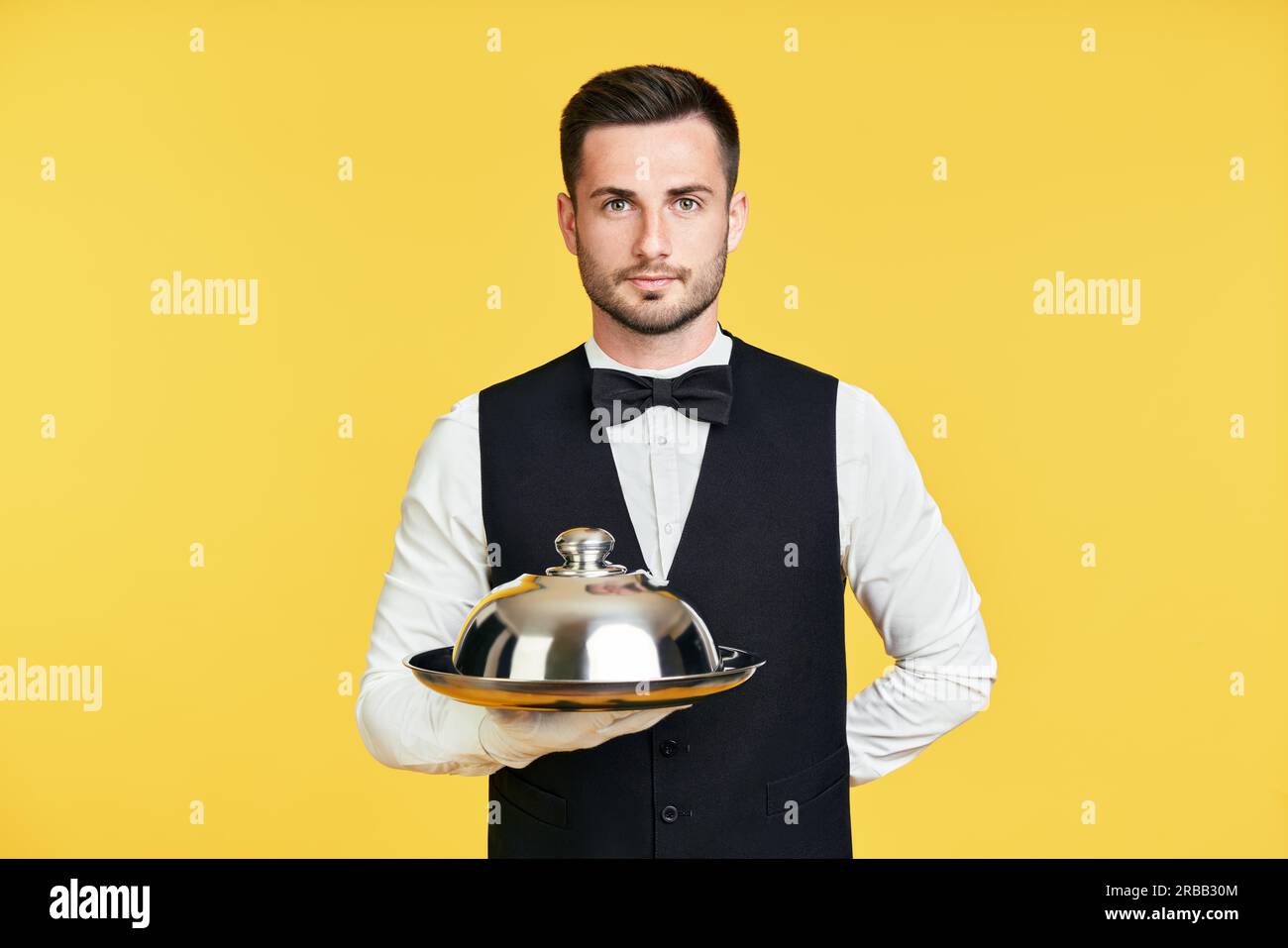Handsome elegant waiter holding tray and cloche ready to serve on ...