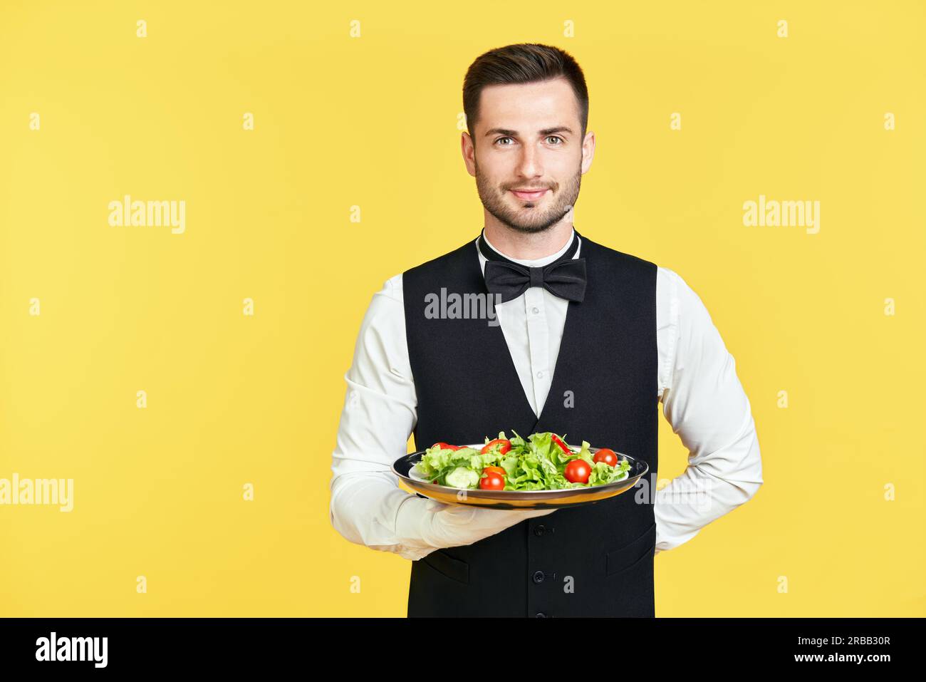 Happy smiling waiter holding plate with healthy vegetable salad ready ...