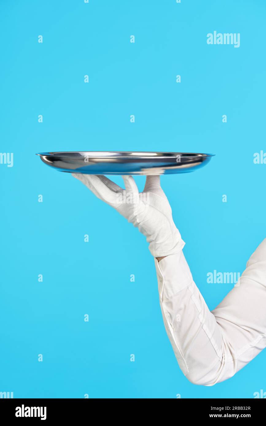 Elegant waiter's hand in white glove holding metal tray on blue ...