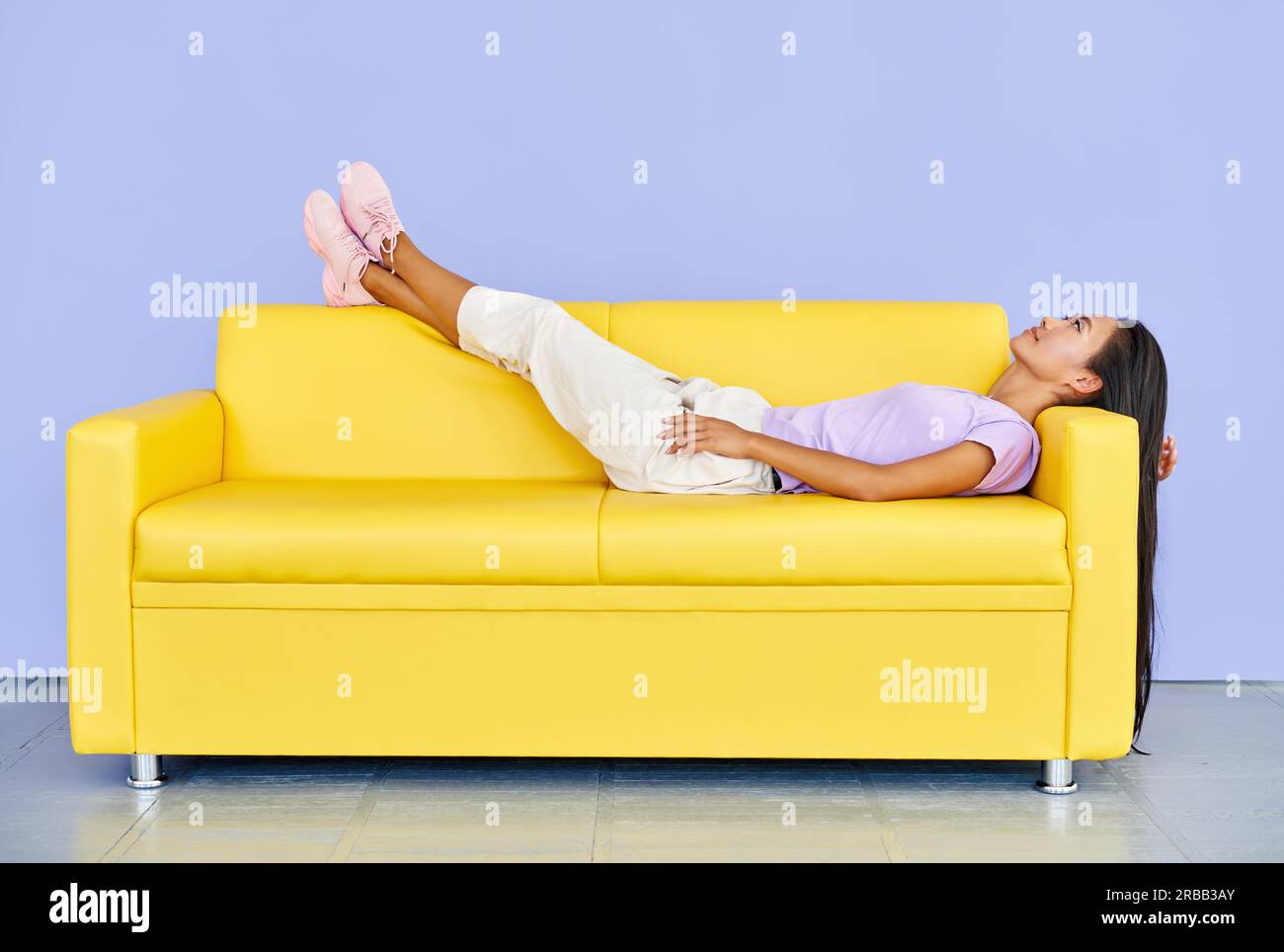Pretty asian woman relax after lying on yellow sofa after hard work ...