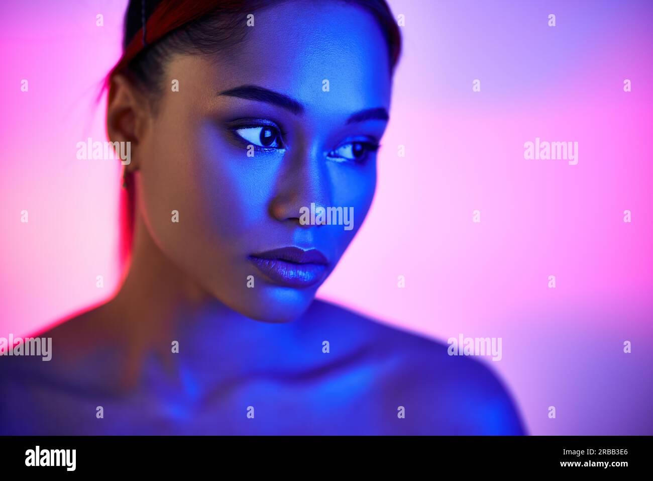 Closeup portrait of pretty african american woman in bright neon lights posing on studio ...