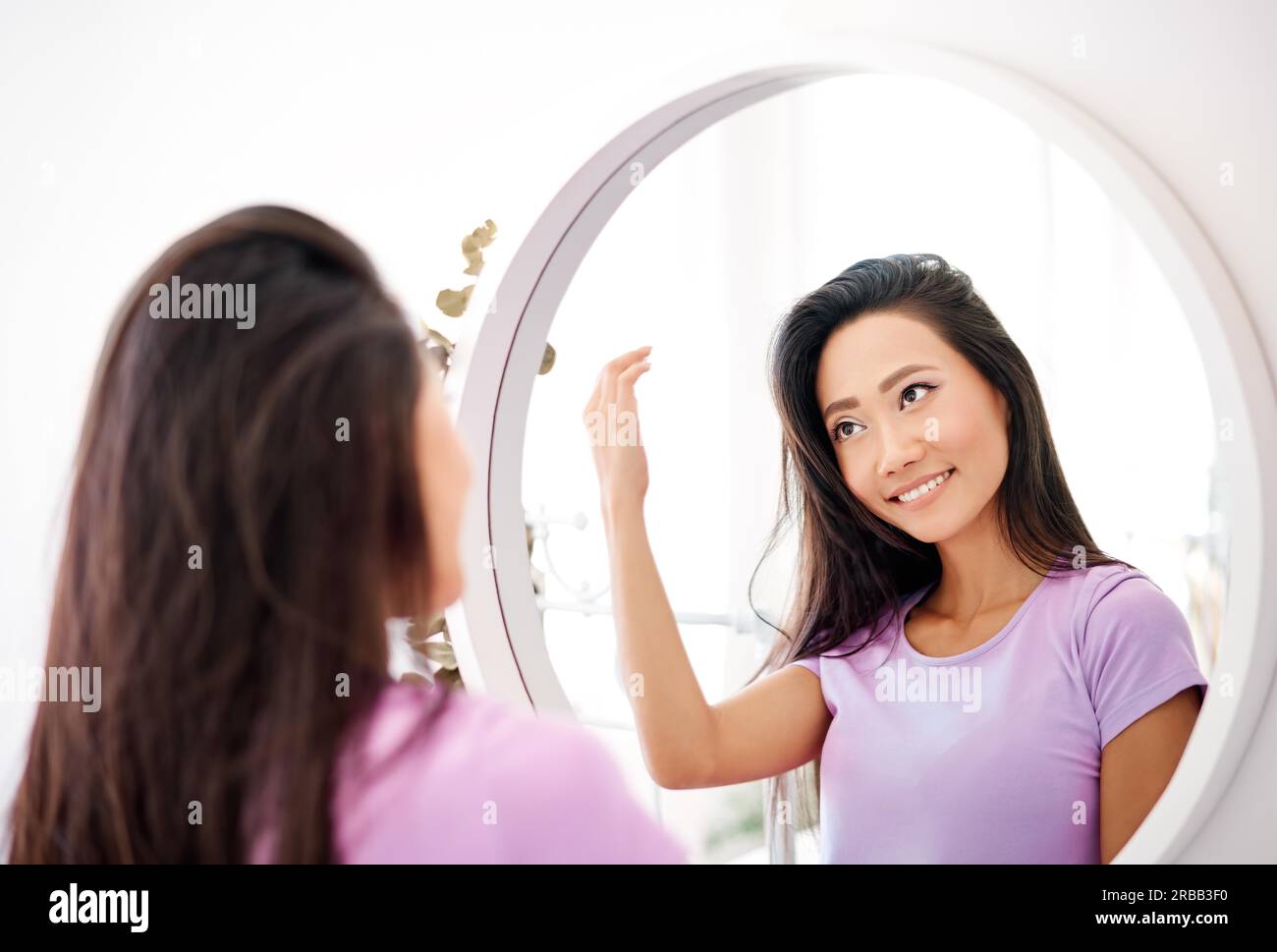 Smiling Beautiful Asian Woman Looking At Herself In The Mirror At Home