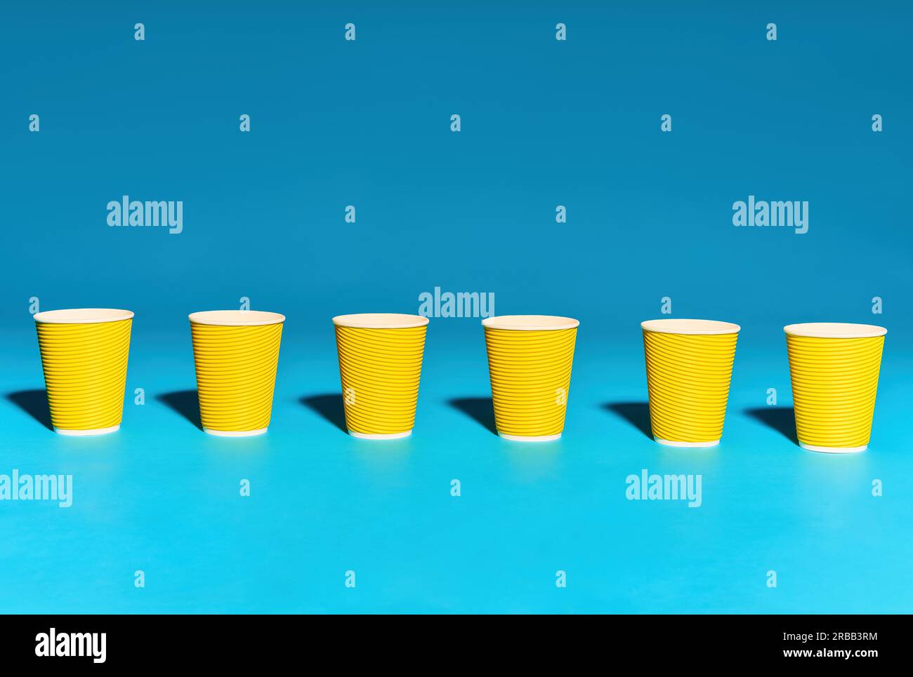 Row of yellow paper cup in line on blue background. creative concept ...