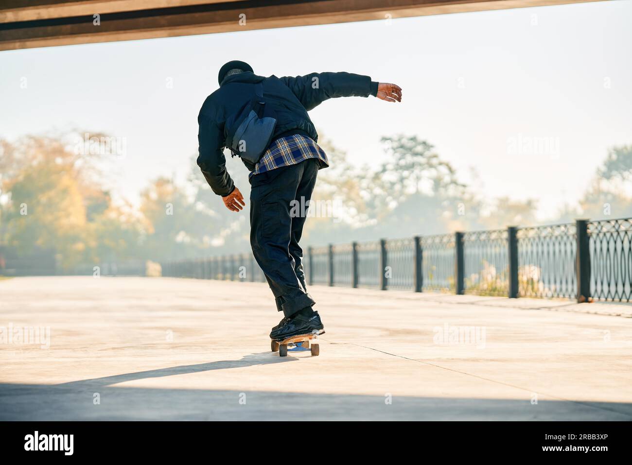 Back view of skateboarder skateboarding on the street urban background ...