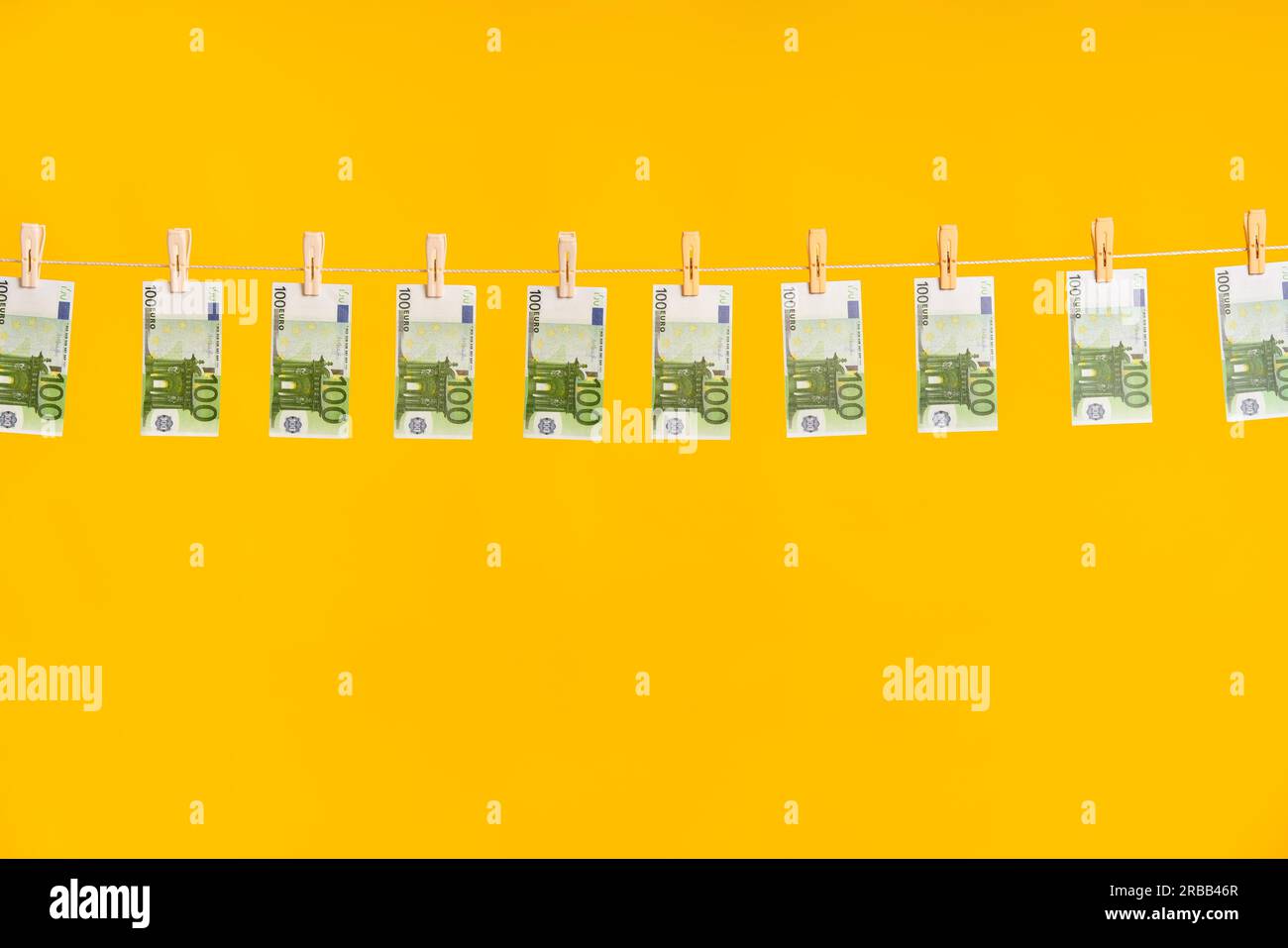 Money laundering, euro banknotes hanging on rope over yellow studio ...