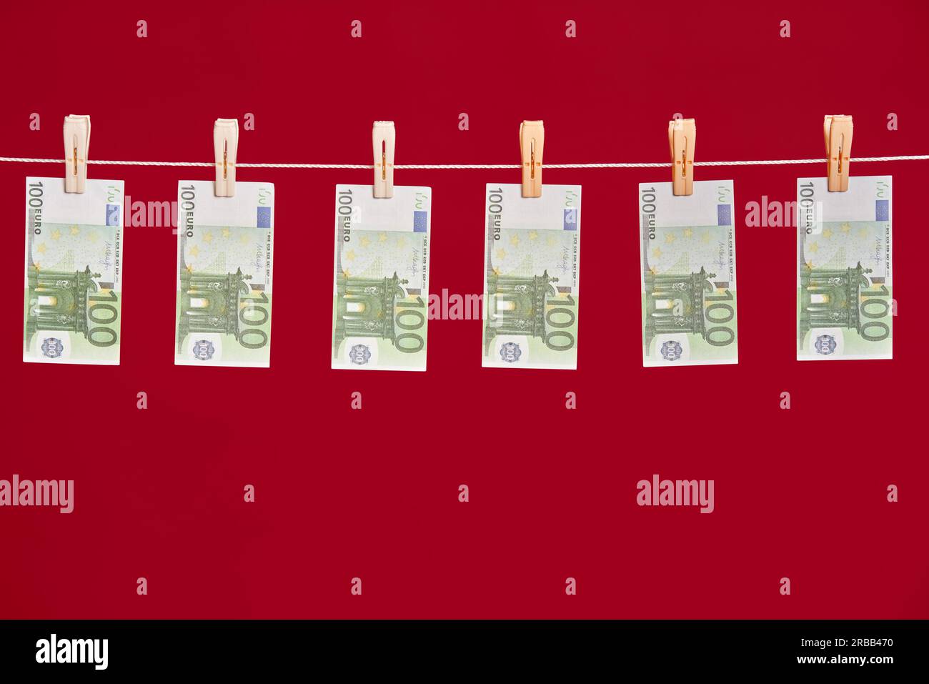 Money laundering, euro banknotes hanging on rope over red studio ...