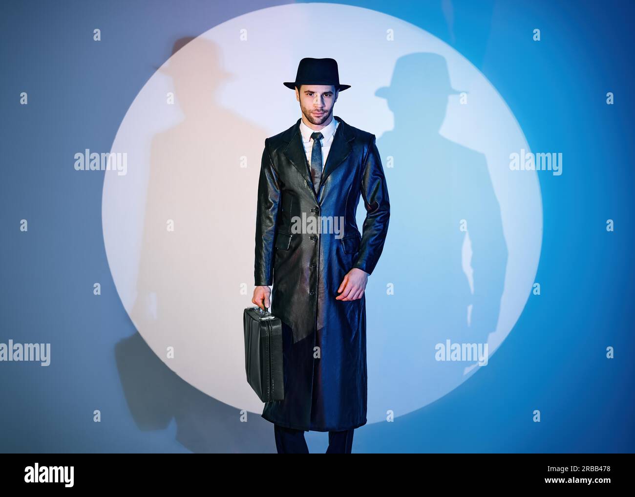 Handsome man in black coat and hat holding briefcase posing in the ...
