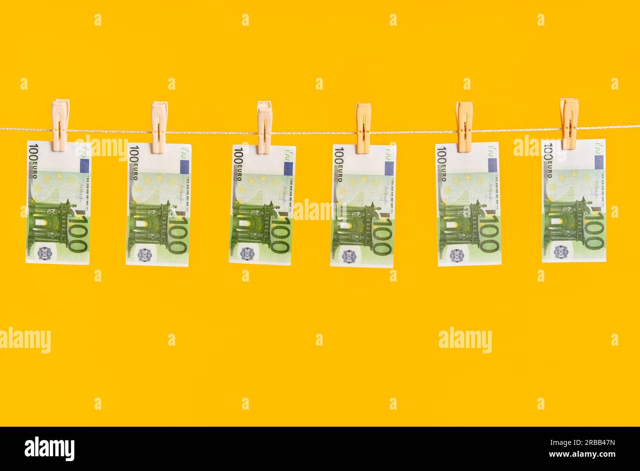 Money laundering, euro banknotes hanging on rope over yellow studio ...