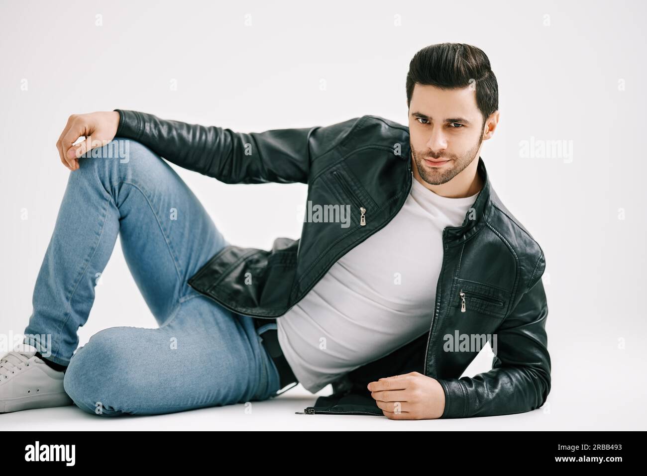 Handsome stylish man posing lying on floor over white studio background ...