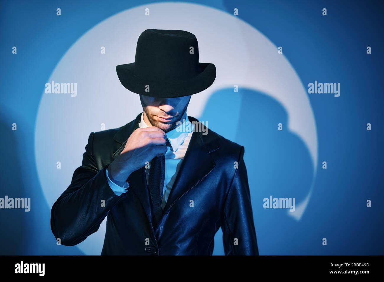 Portrait of handsome man in black coat hiding face behind his hat in ...