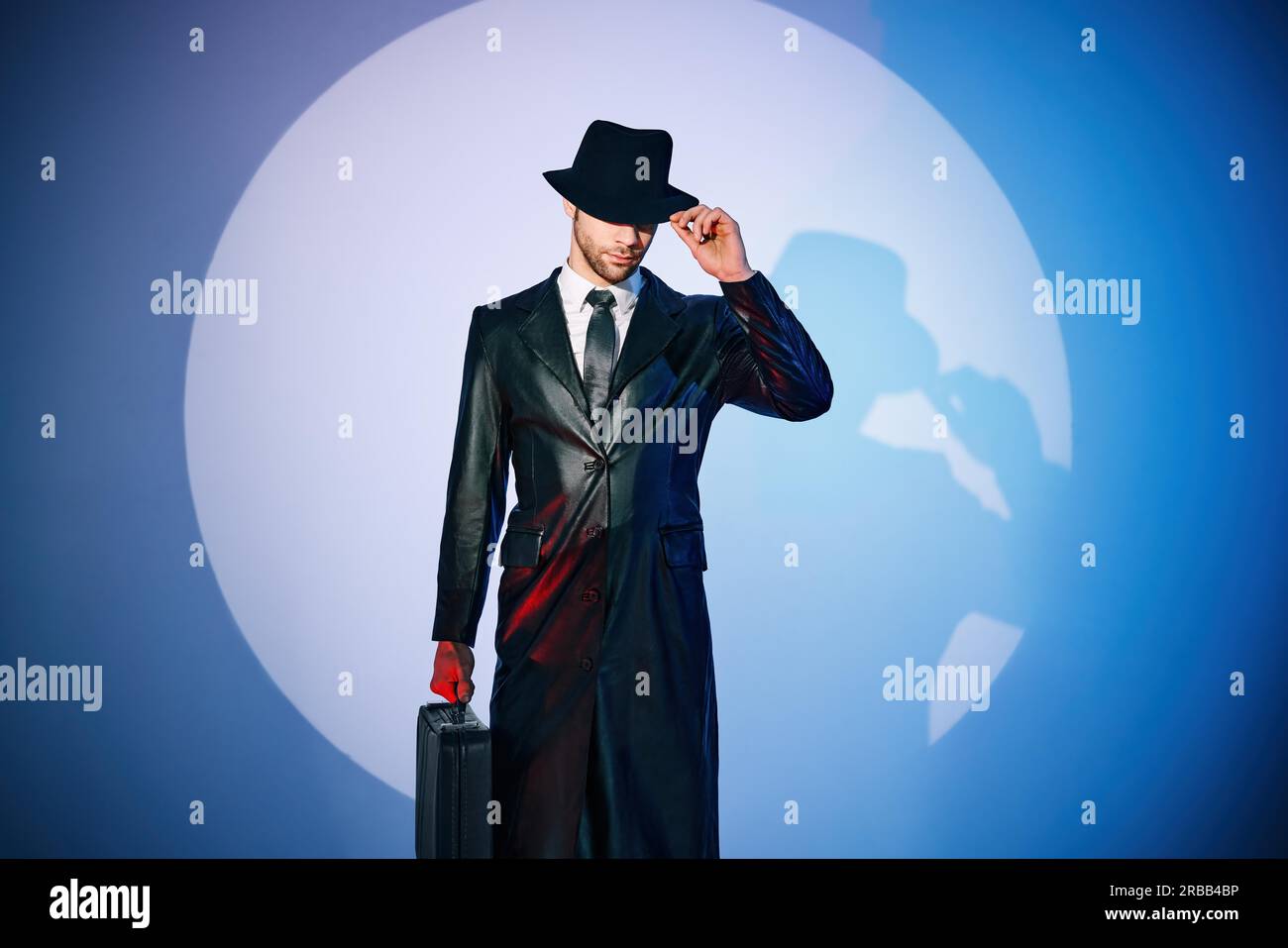 Portrait of handsome man in black coat and hat holding briefcase posing ...
