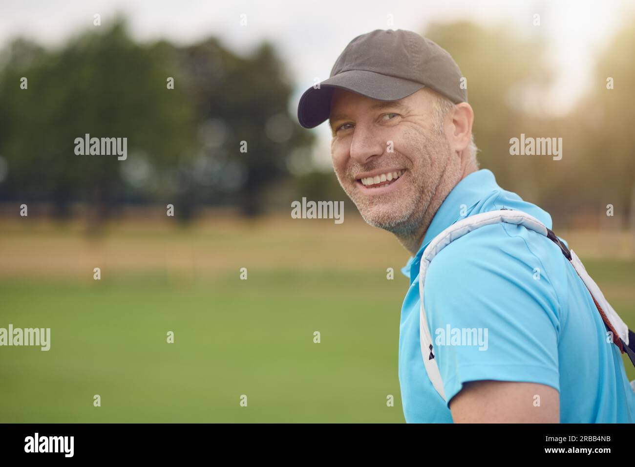 Smiling friendly middle-aged golfer turning to look back over his ...