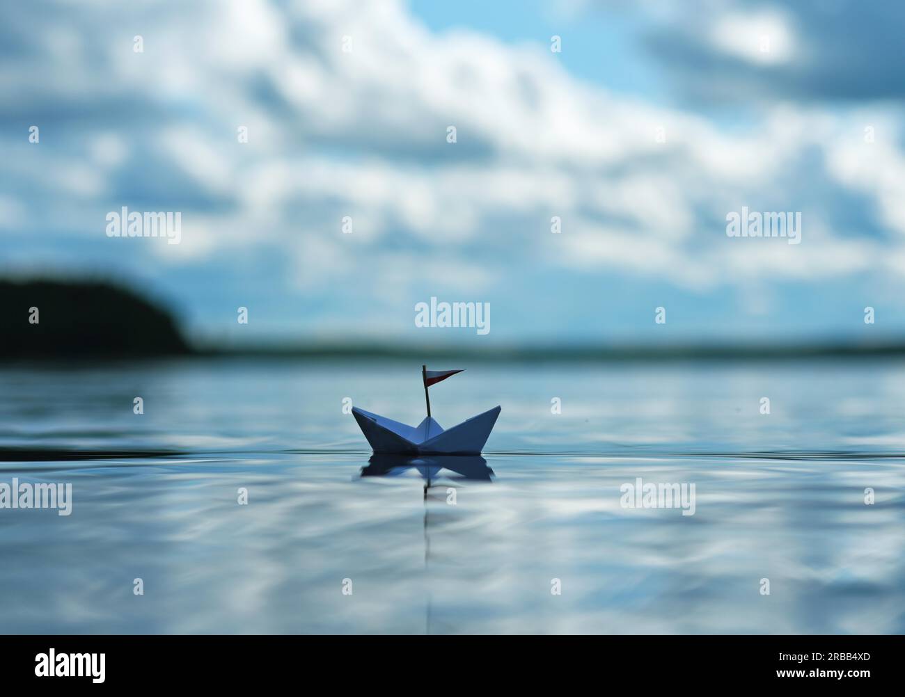 Small paper ship on a glittering lake Stock Photo - Alamy