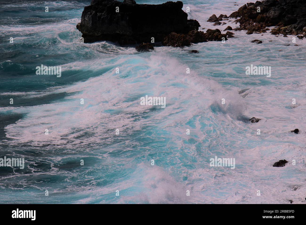 Small waves, with white caps, in varied shades of blue, meeting the ...