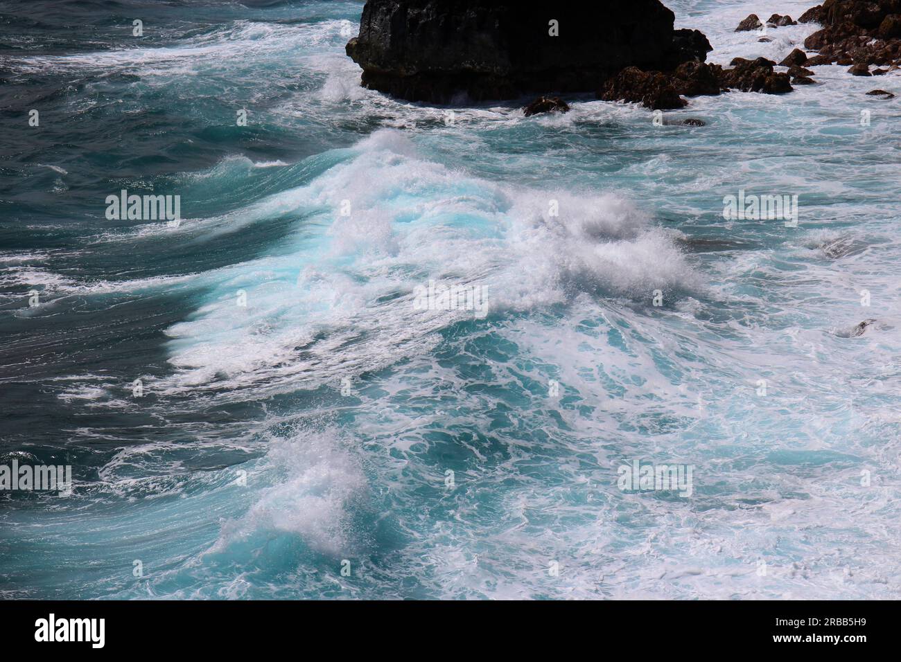 Small waves, with white caps, in varied shades of blue, meeting the ...