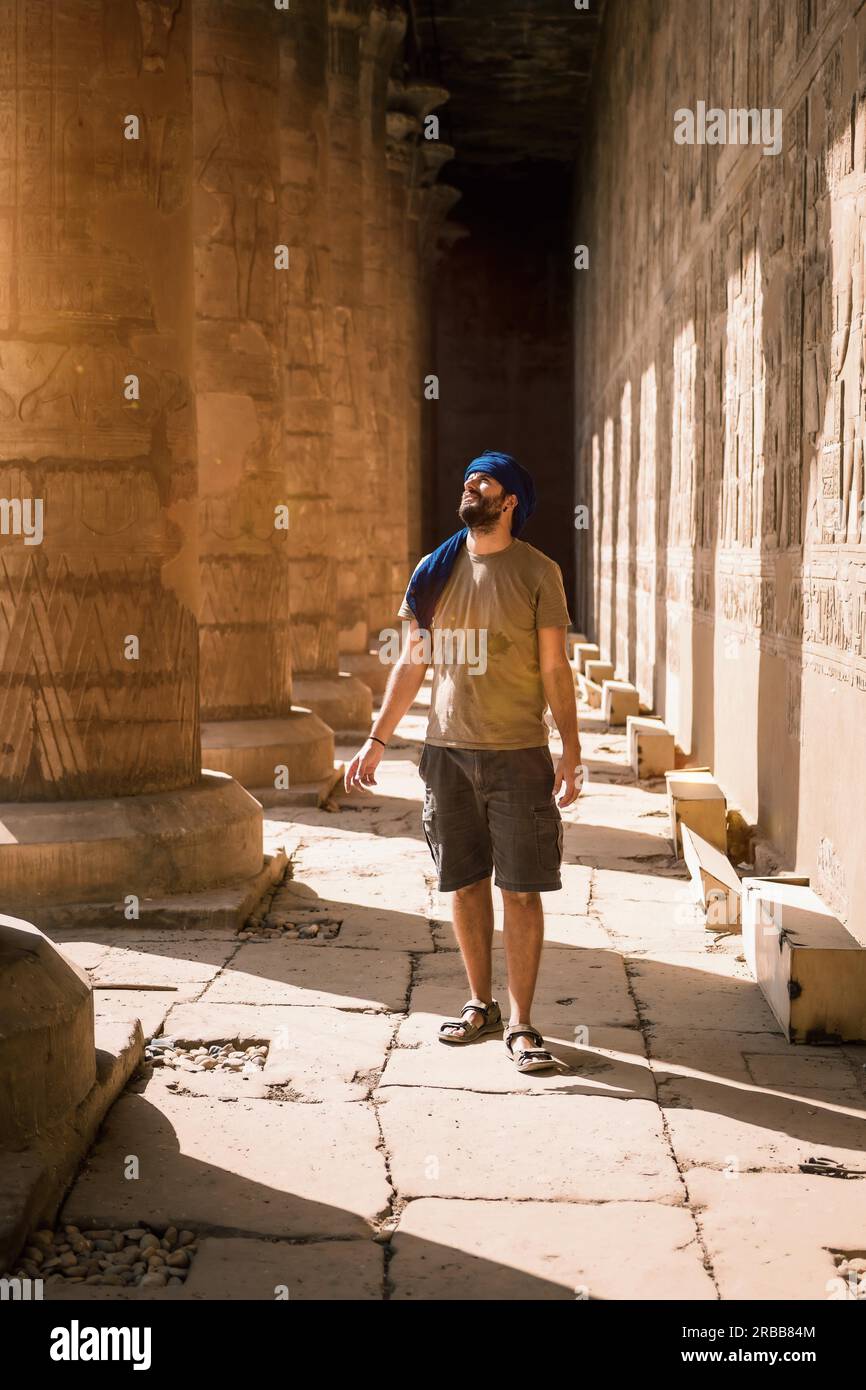 Young man in blue turban walking on the columns of the Edfu Temple near ...