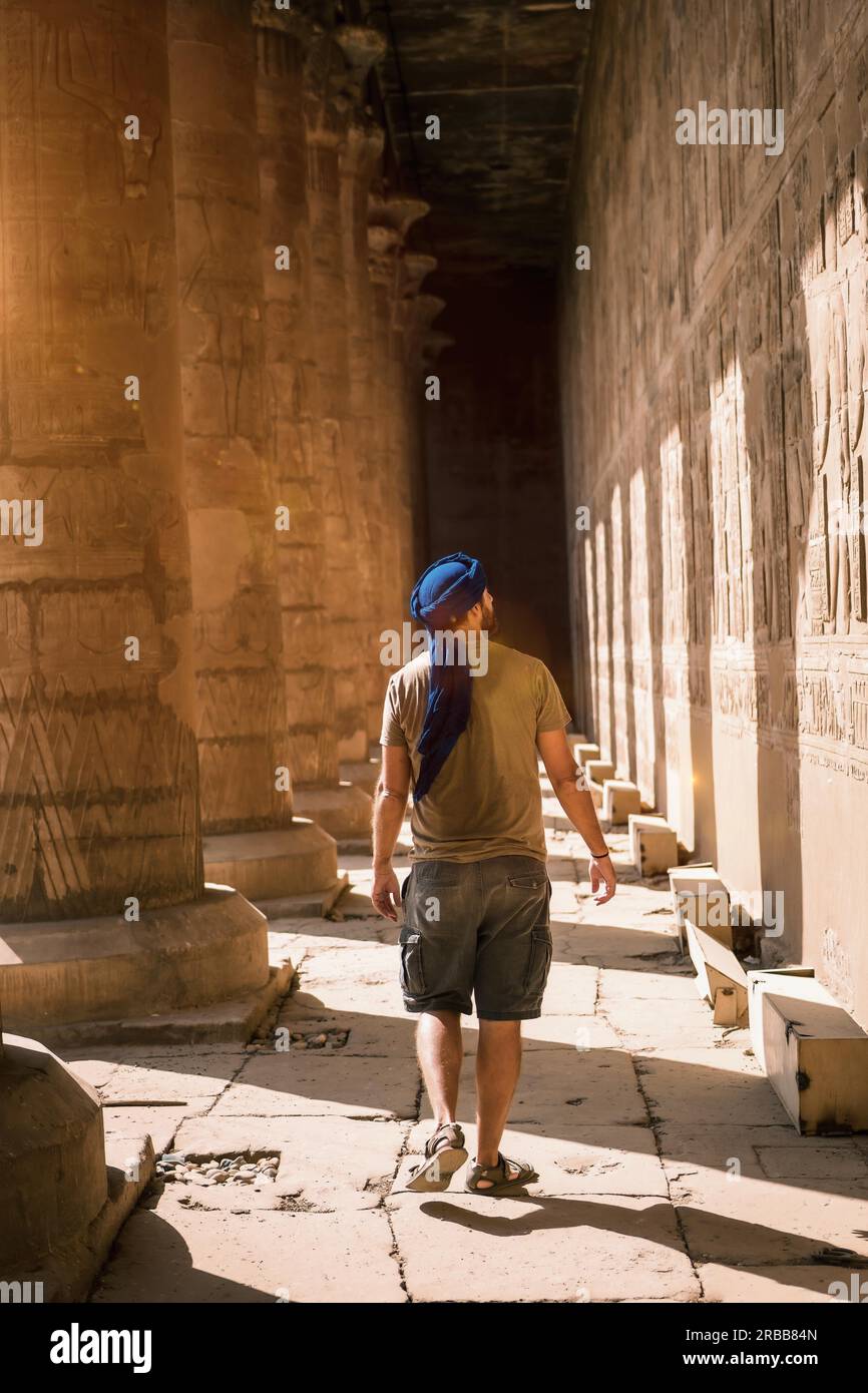 Young man in blue turban walking on the columns of the Edfu Temple near ...