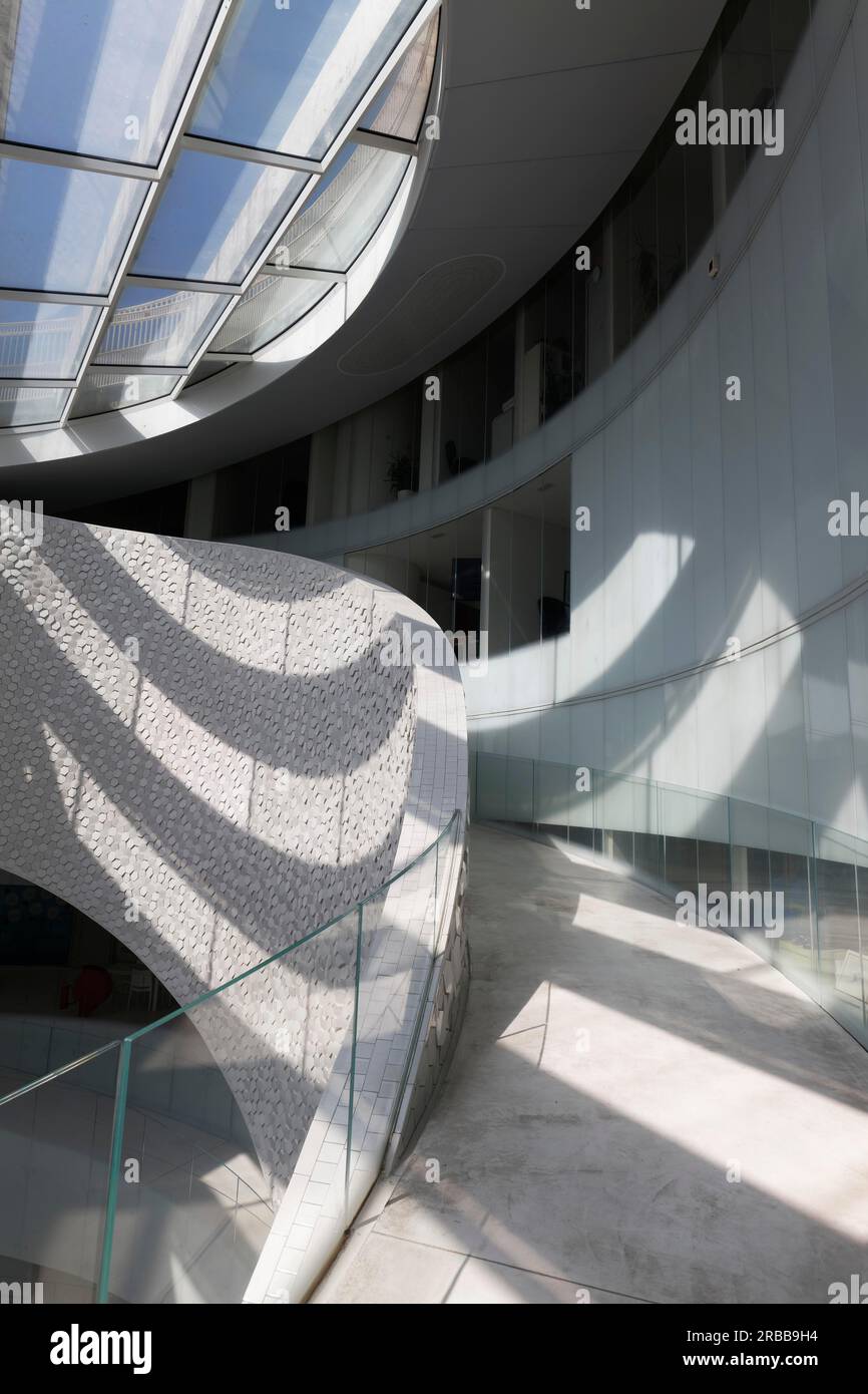 Futuristic atrium with light and shadow, walls clad in white tiles in ...