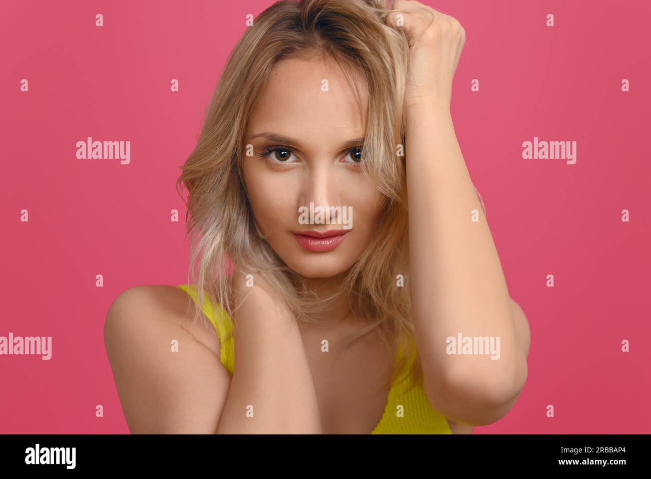 Attractive young blond woman with hands to her hair looking at the ...