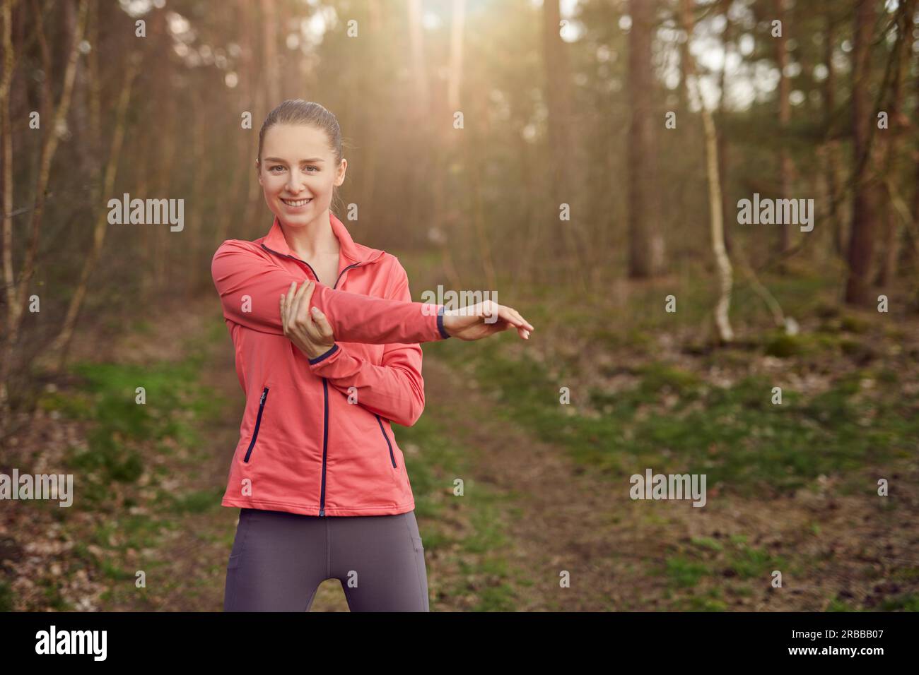 Front view portrait of a happy fit woman stretching her arm during ...