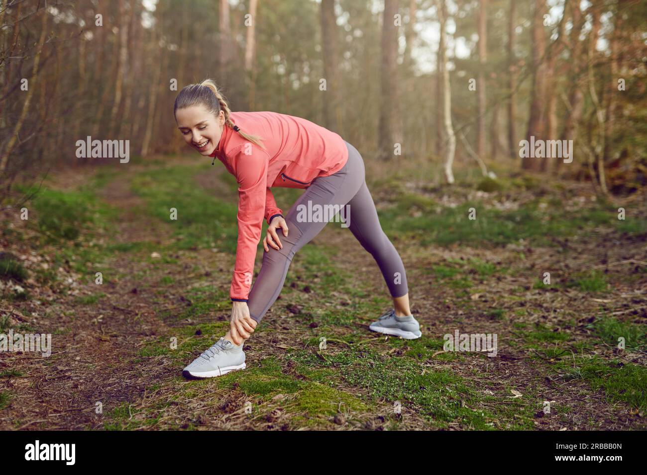 Full length portrait of a cheerful fit young woman doing stretching ...