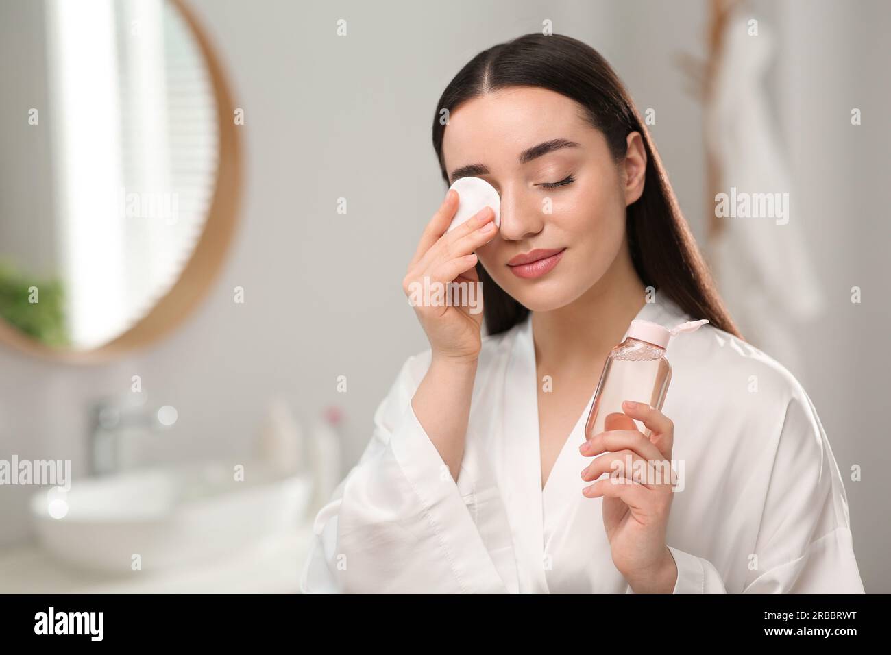 Beautiful woman removing makeup with cotton pad indoors Stock Photo - Alamy
